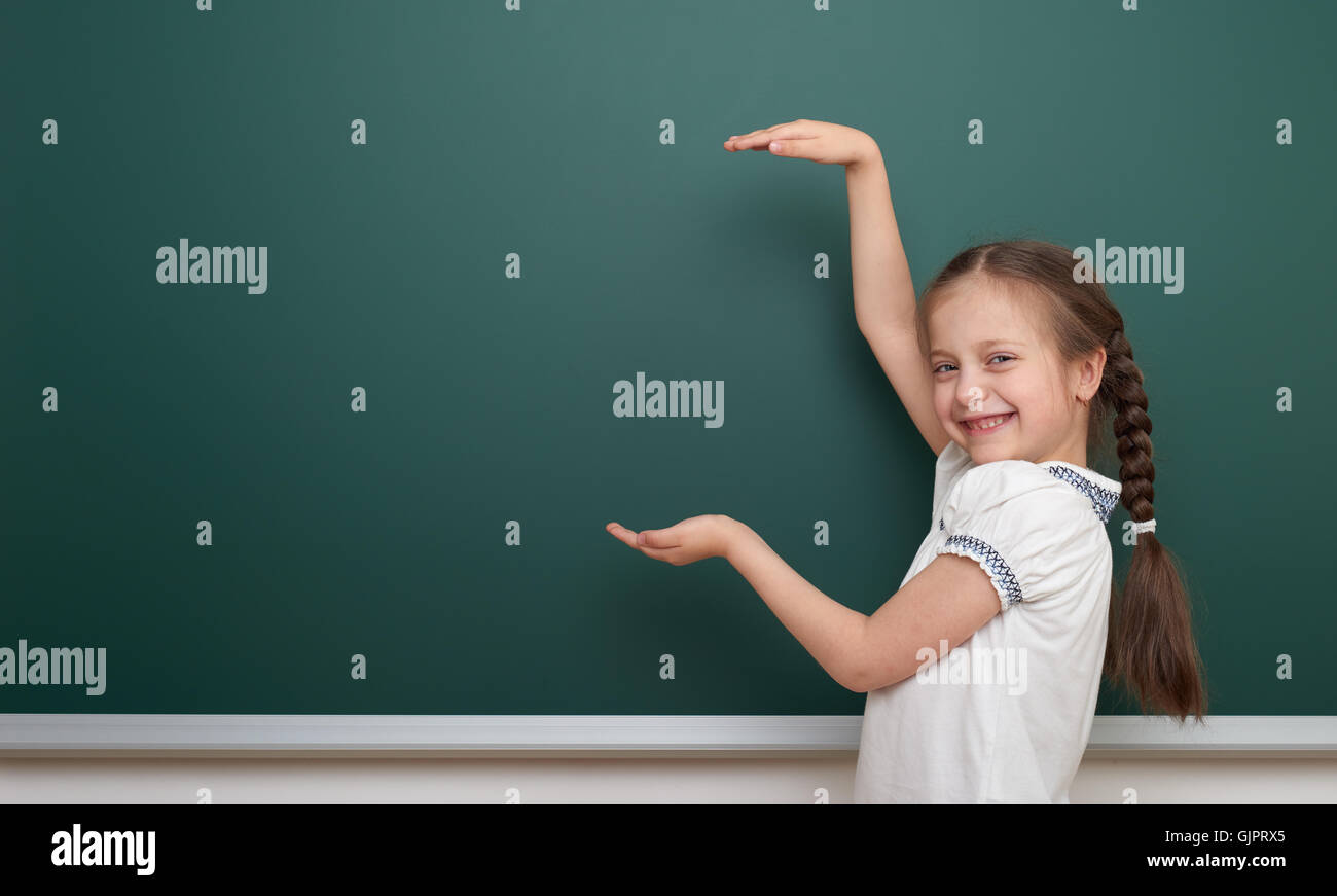 school student girl open arms at the clean blackboard, grimacing and ...