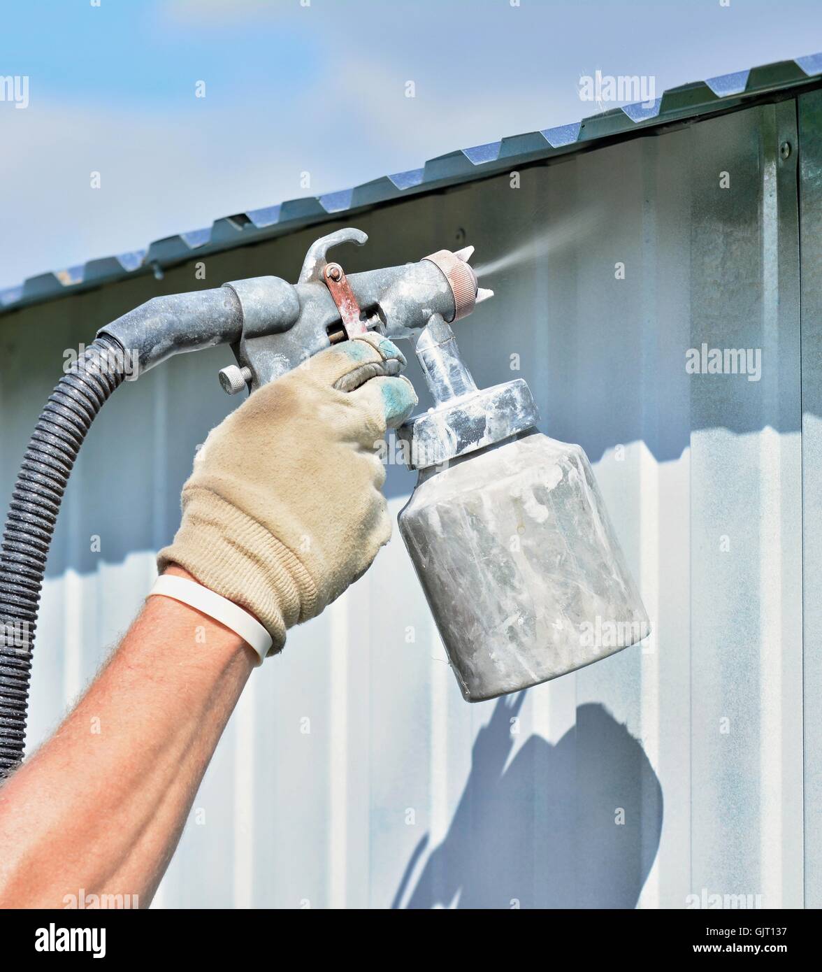 Spraying white paint onto a galvanized surface by an airbrush gun Stock ...