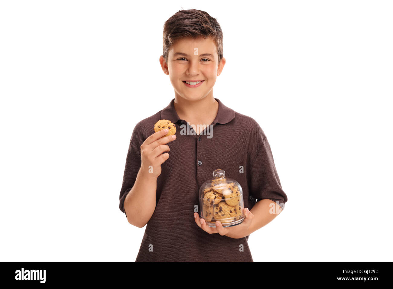 Cheerful child holding a cookie in one hand and a jar of cookies in the ...