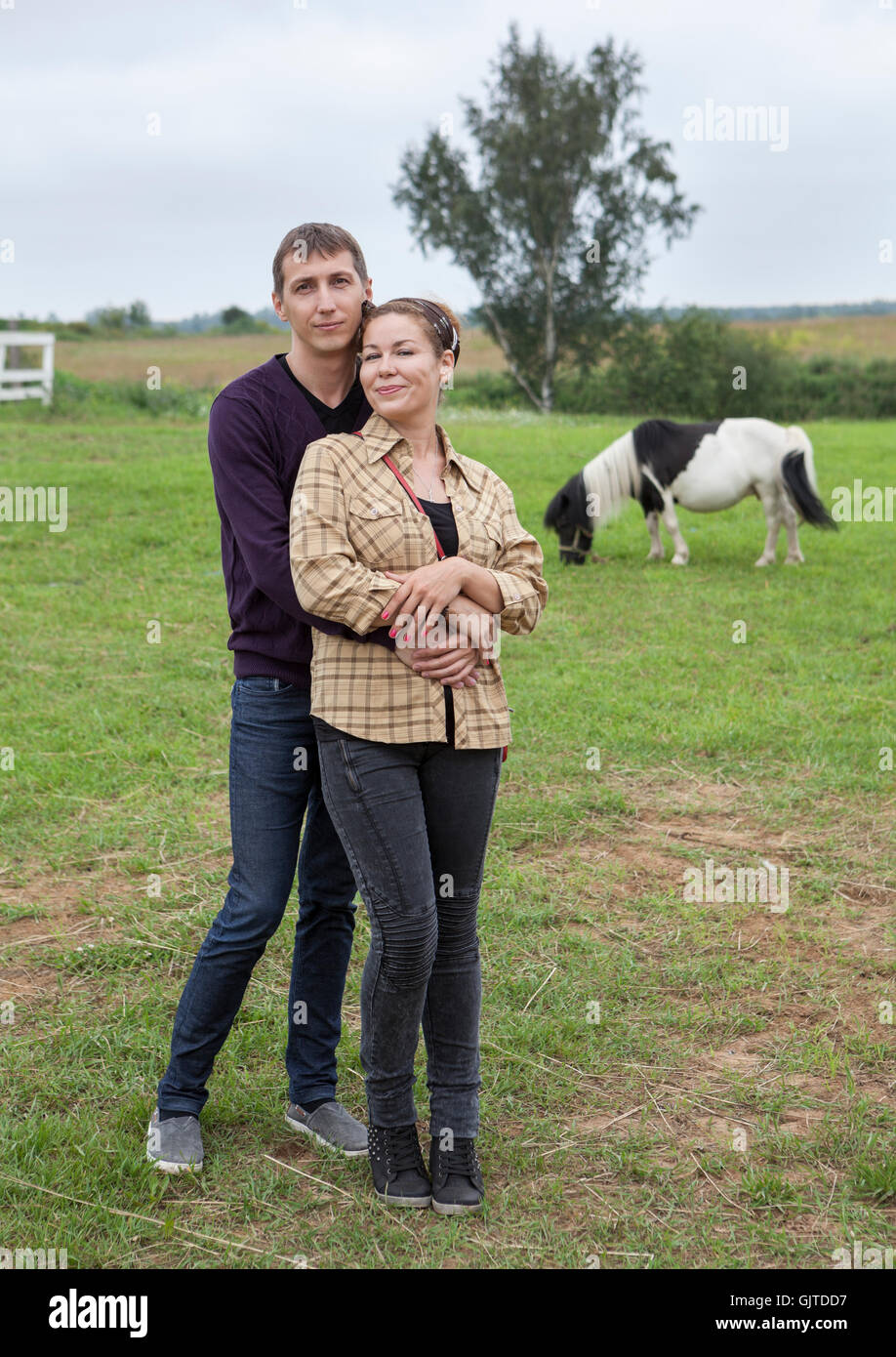 Loving couple standing in farm with pony horse on background Stock ...