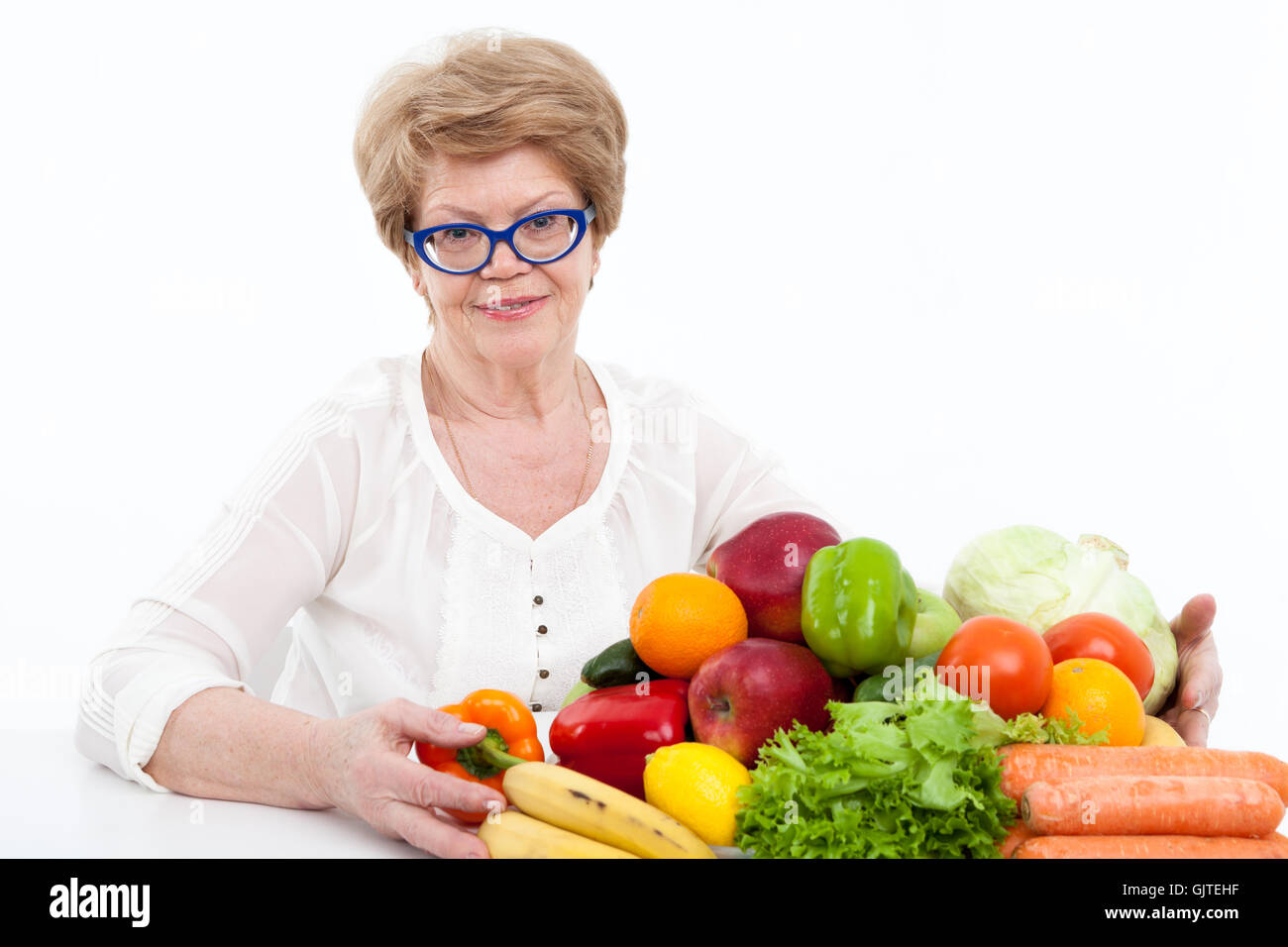 Attractive elder Caucasian woman embracing fresh vegetables and fruits ...