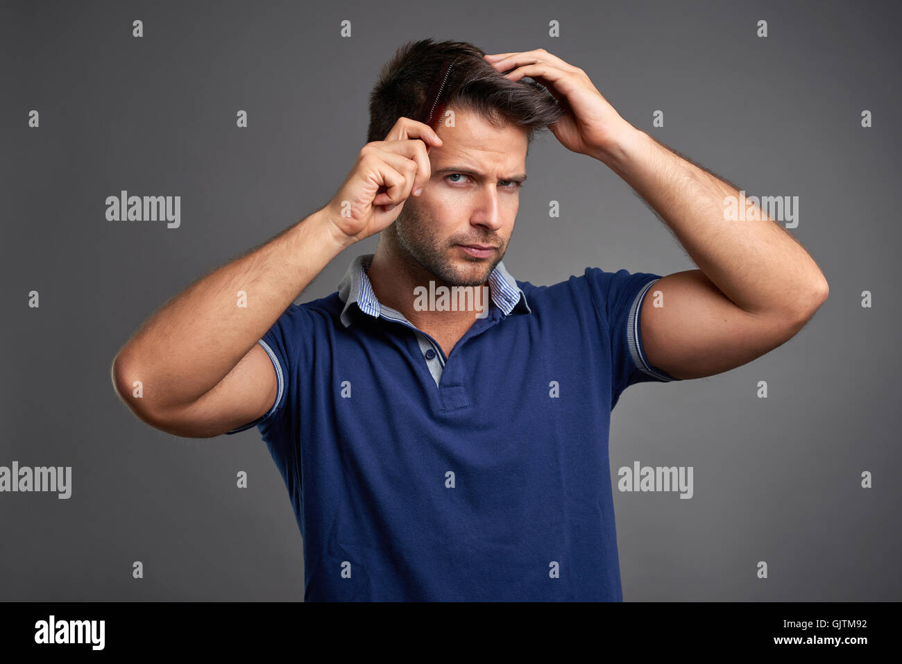 A serious handsome young man combing his hair Stock Photo - Alamy