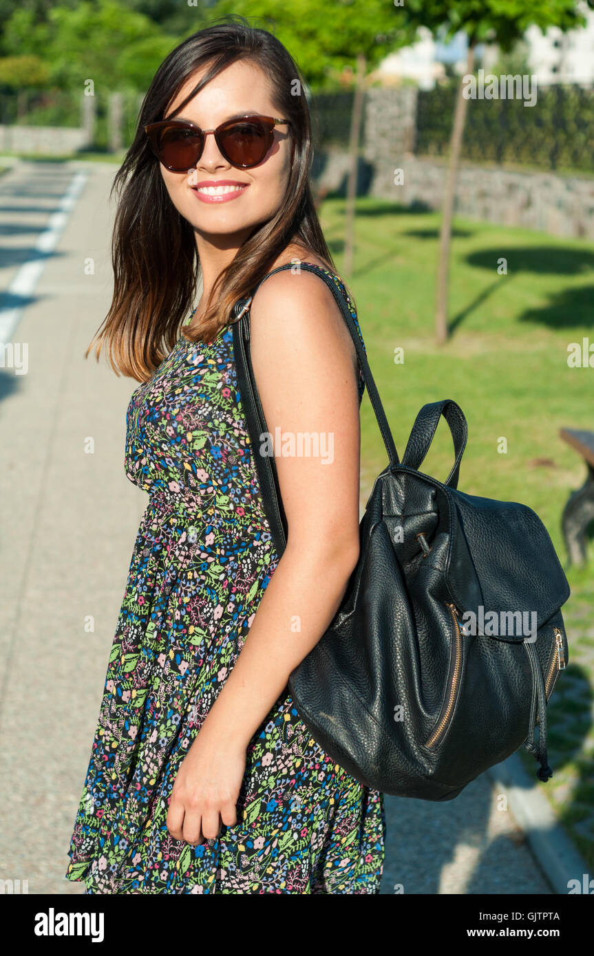 Beautiful young lady posing and smiling in park wearing summer dress ...