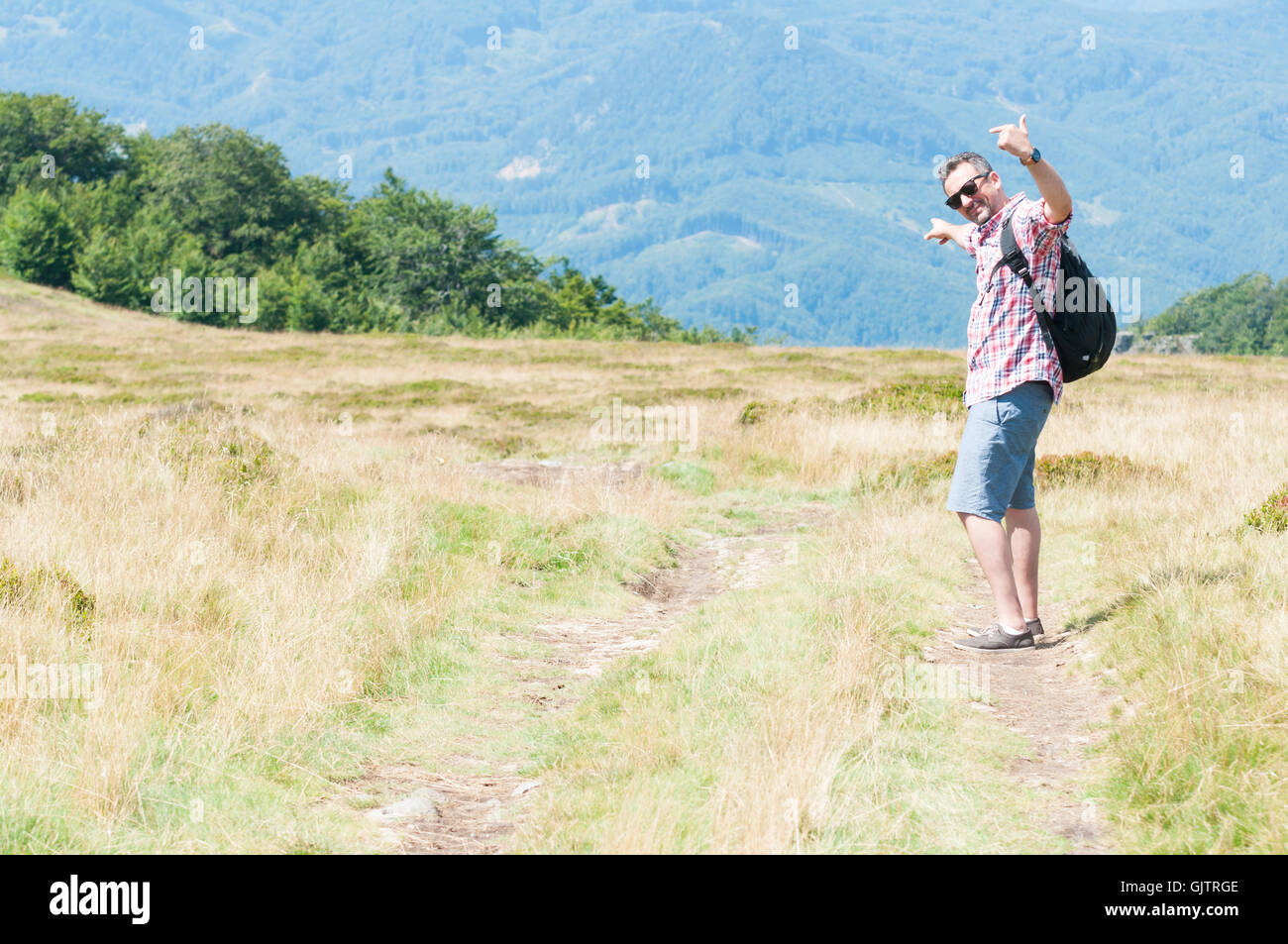 Backpacker on footpath showing or pointing the way in a sunny summer ...