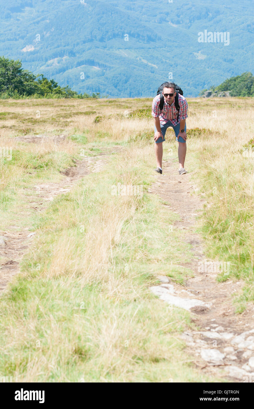 Backpacker on mountain footpath feeling tired or exhausted in sunny day ...