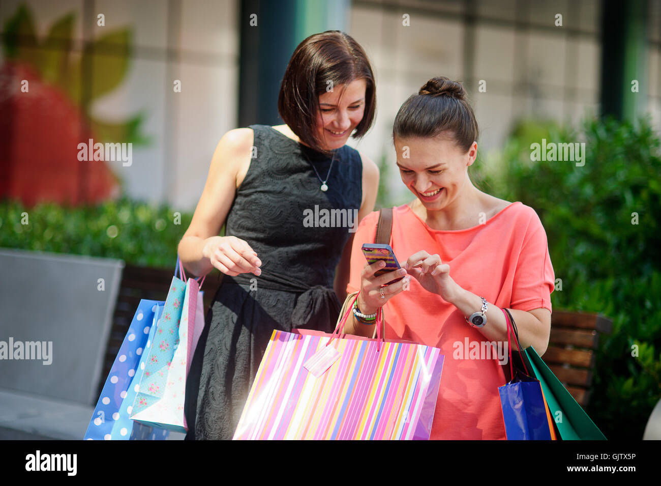 Two charming women close to the shopping center. In the hands of women ...