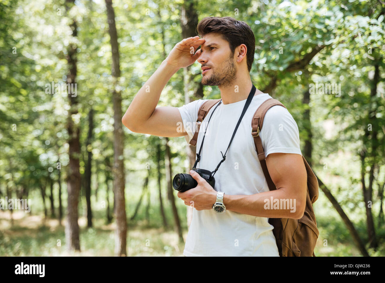 Serious young man photographer with modern photo camera standing and ...