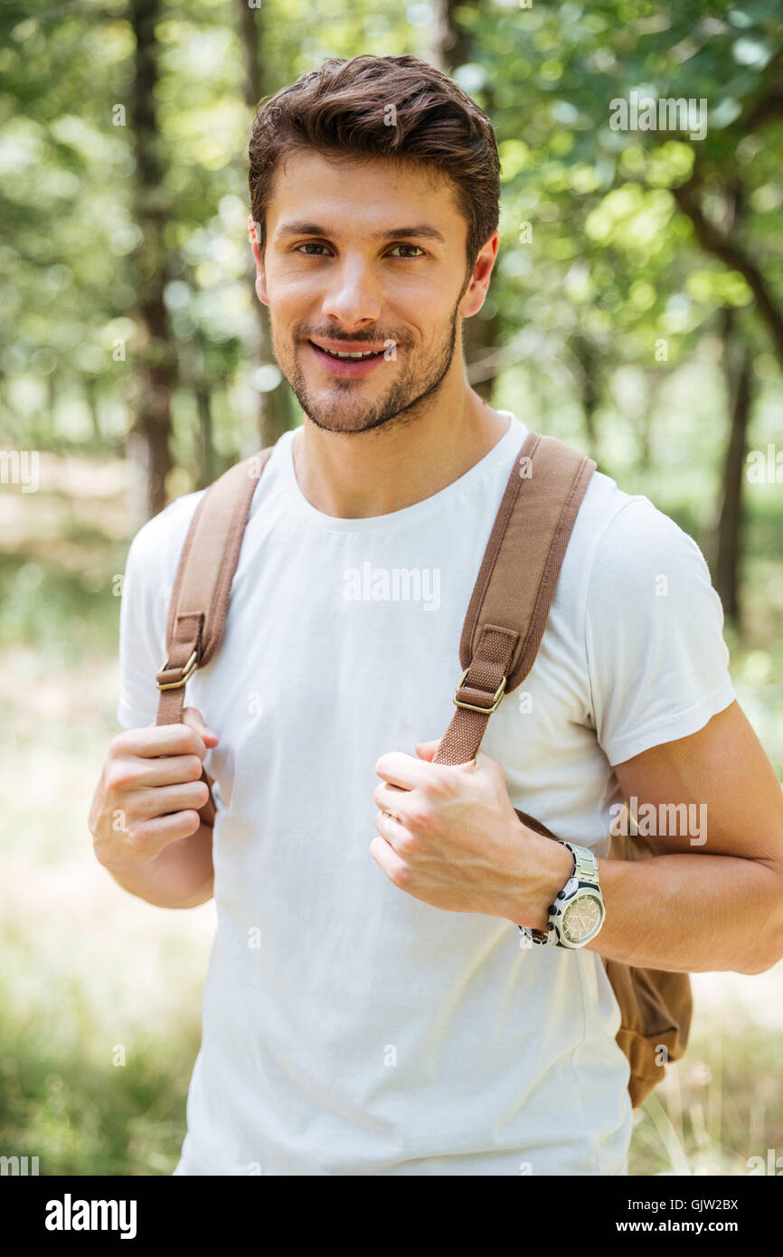 Portrait of happy handsome young man with backpack standing outdoors ...