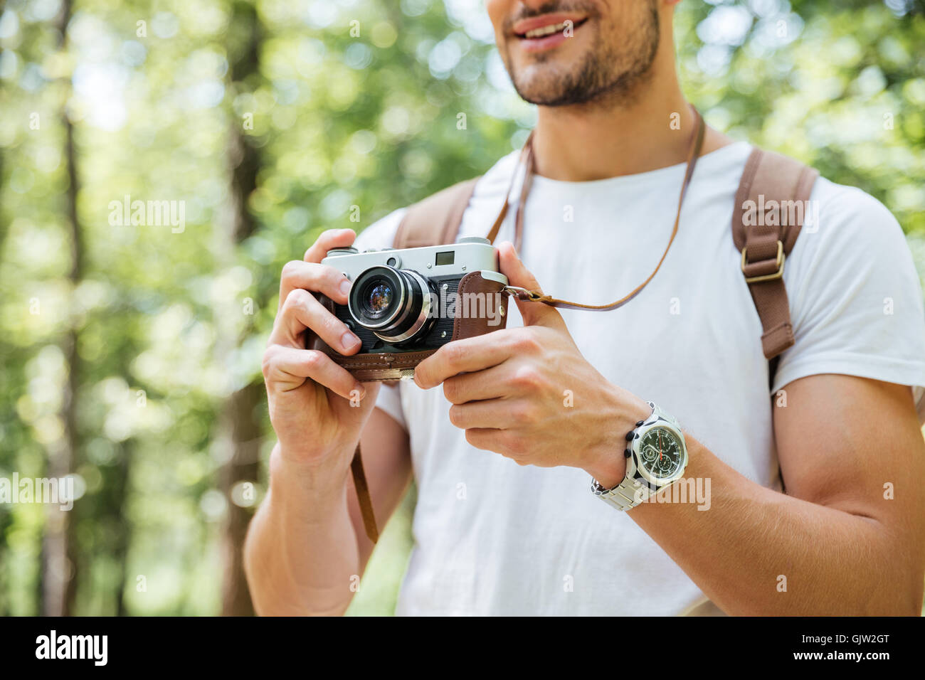 Closeup of smiling young man with backpack standing and taking photos ...