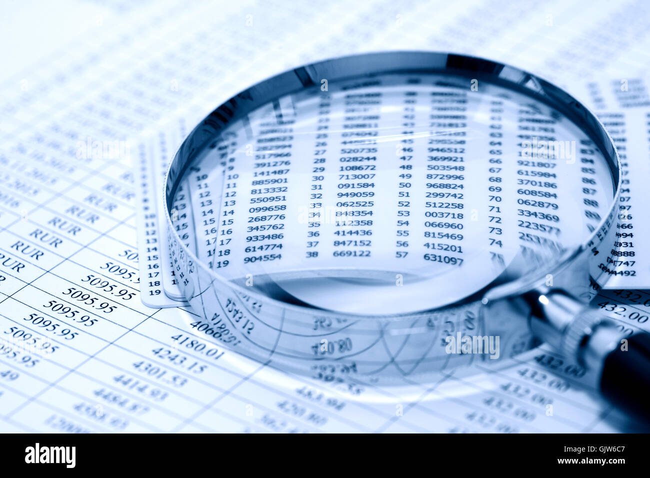 Business concept. Magnifying glass on paper background with digits ...