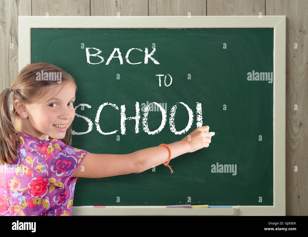 a pretty girl writting back to school on blackboard Stock Photo - Alamy