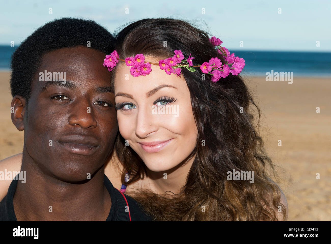 Young couple multicultural mixed race head shot heads together on beach ...