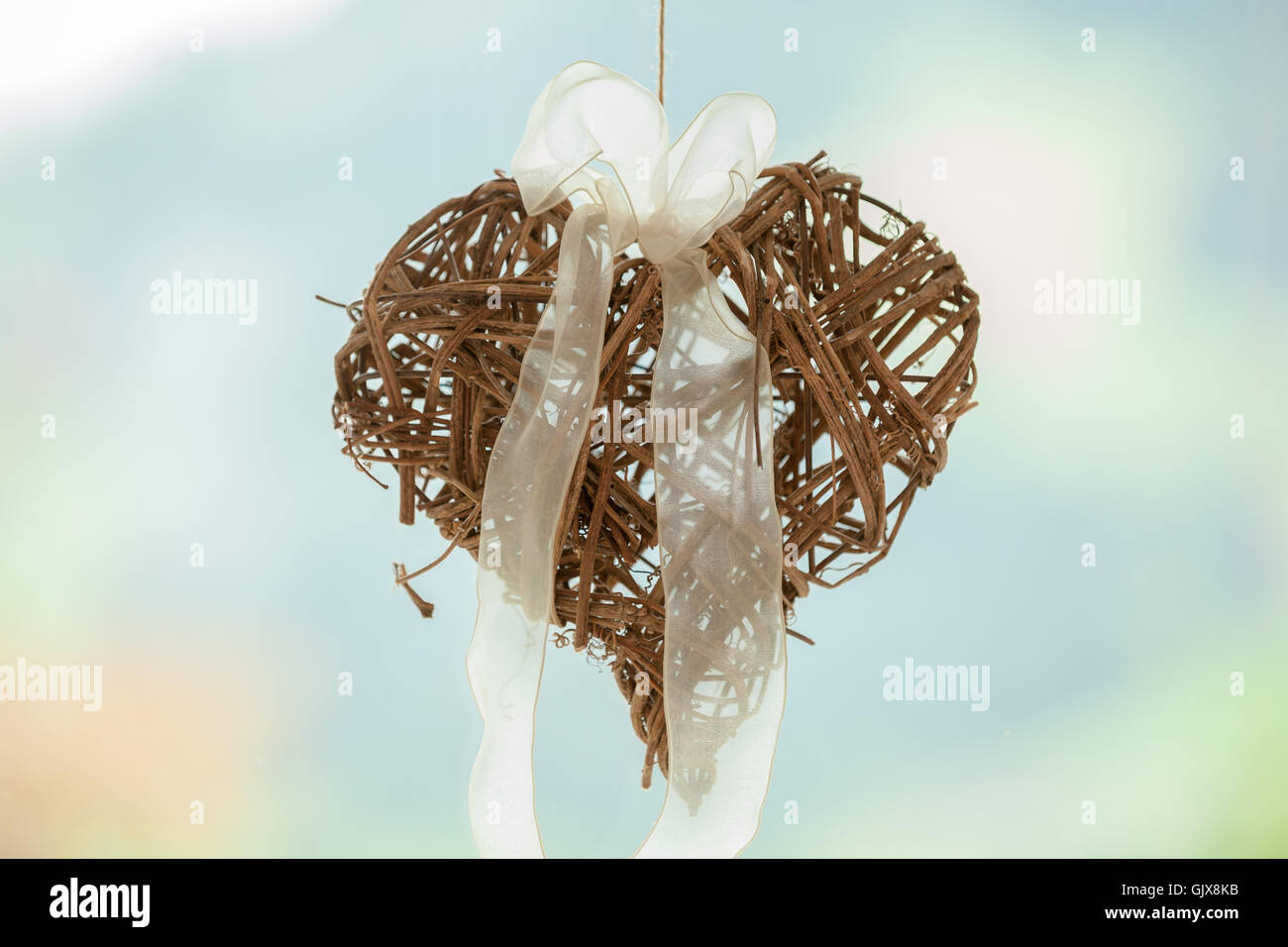Heart from twigs with a white ribbon hanging on a window Stock Photo ...