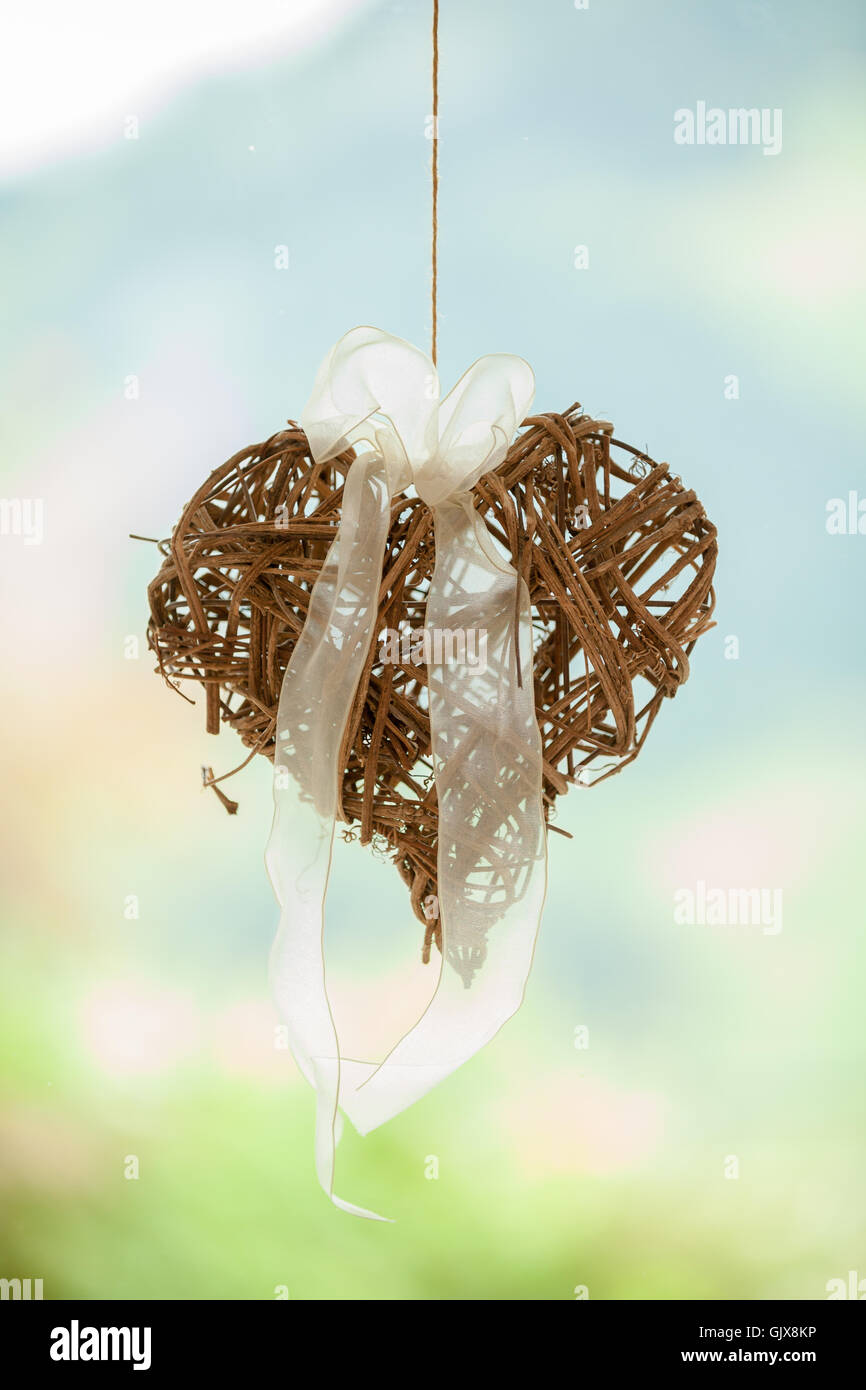Heart from twigs with a white ribbon hanging on a window Stock Photo ...