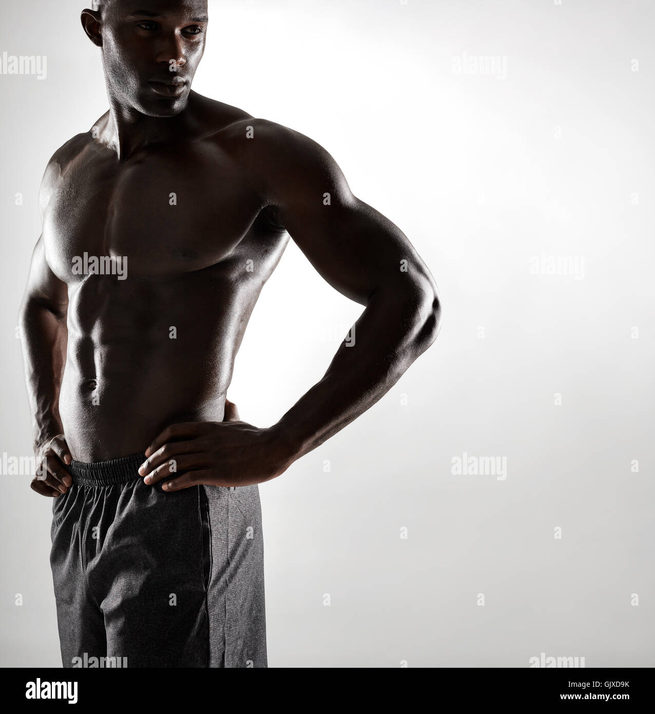 Portrait of muscular man standing with his hands on hips looking away with an attitude. Strong ...