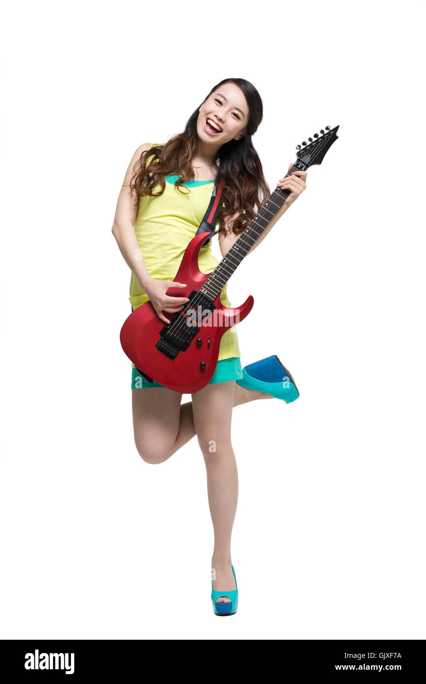 Fashion studio shot of young women while playing the guitar and dancing ...
