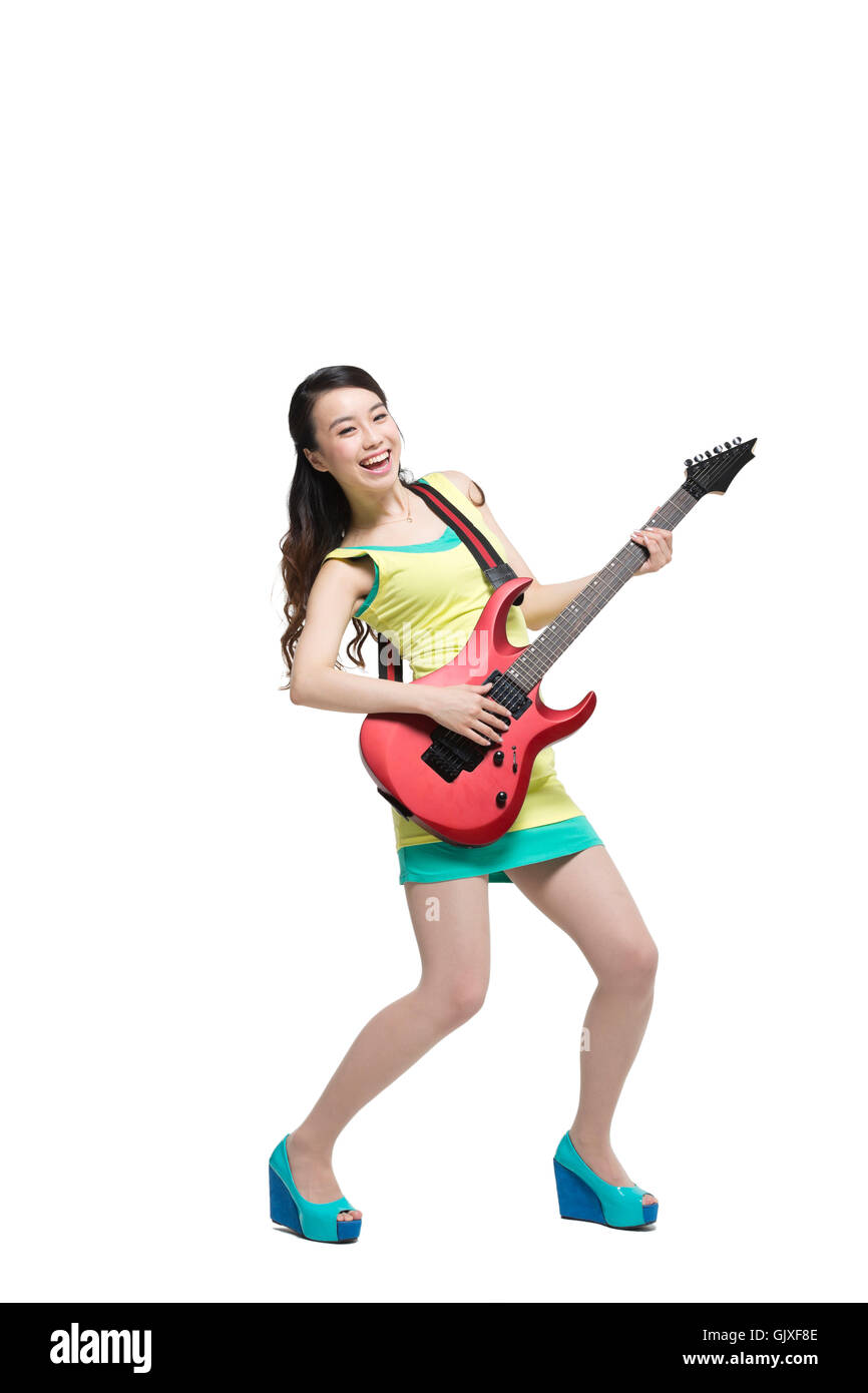Fashion studio shot of young women while playing the guitar and dancing ...