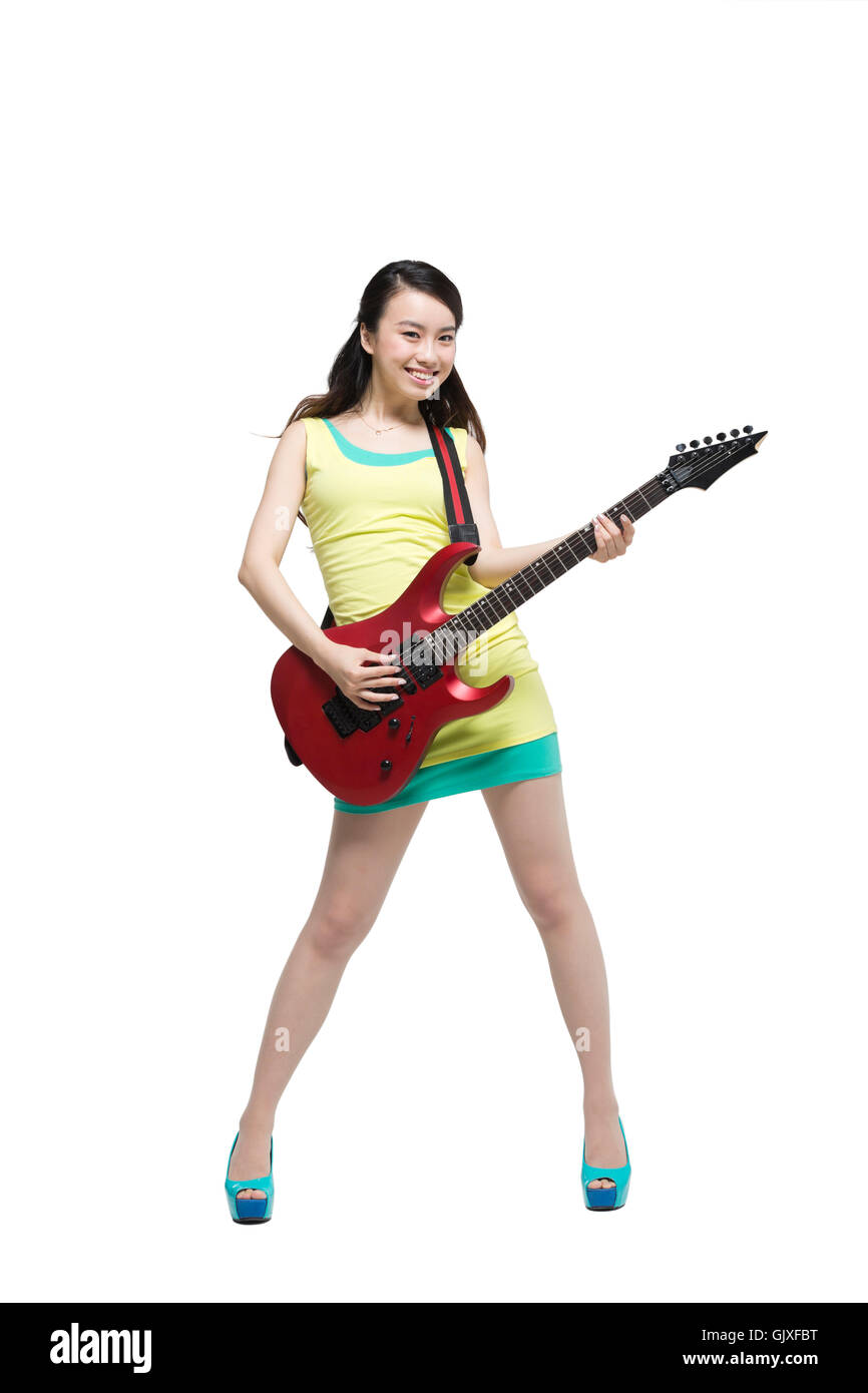 Fashion studio shot of young women while playing the guitar and dancing ...