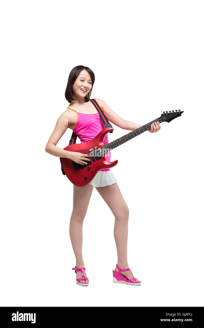 Fashion studio shot of young women while playing the guitar and dancing ...