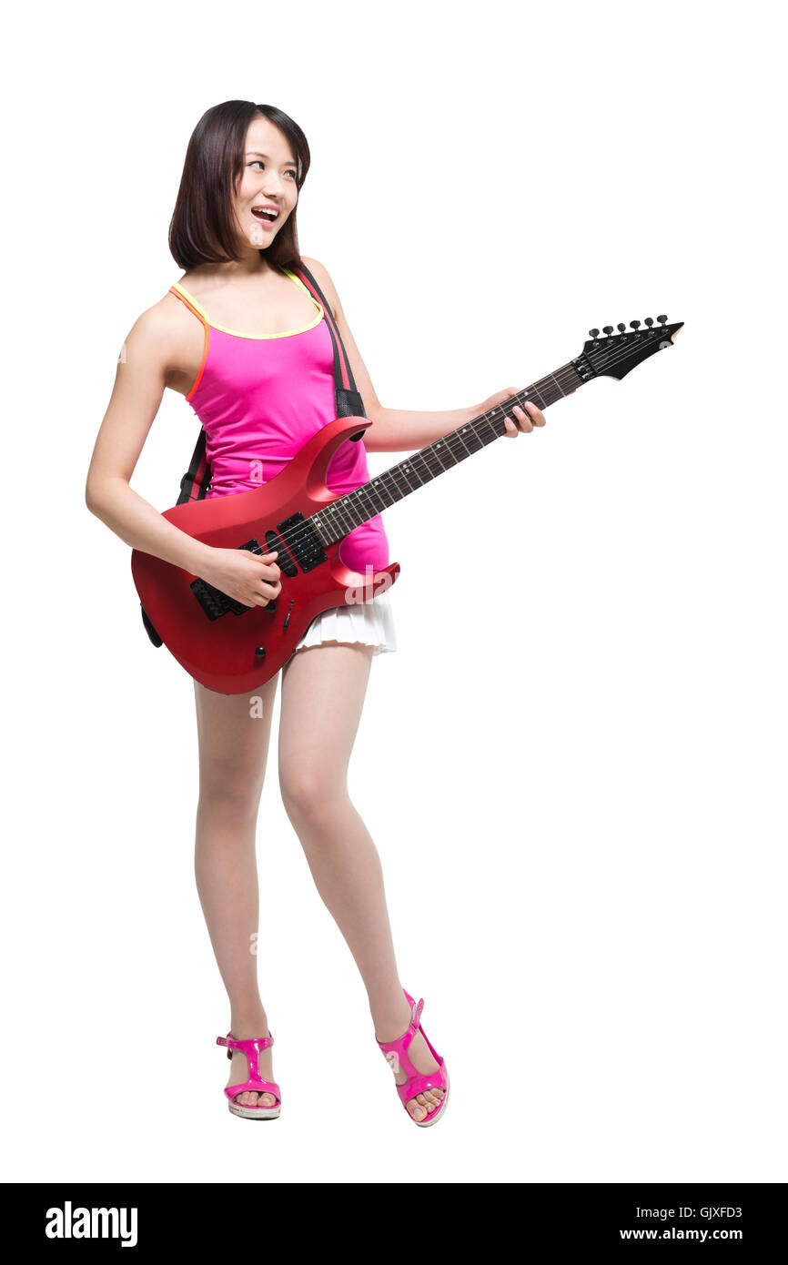 Fashion studio shot of young women while playing the guitar and dancing ...