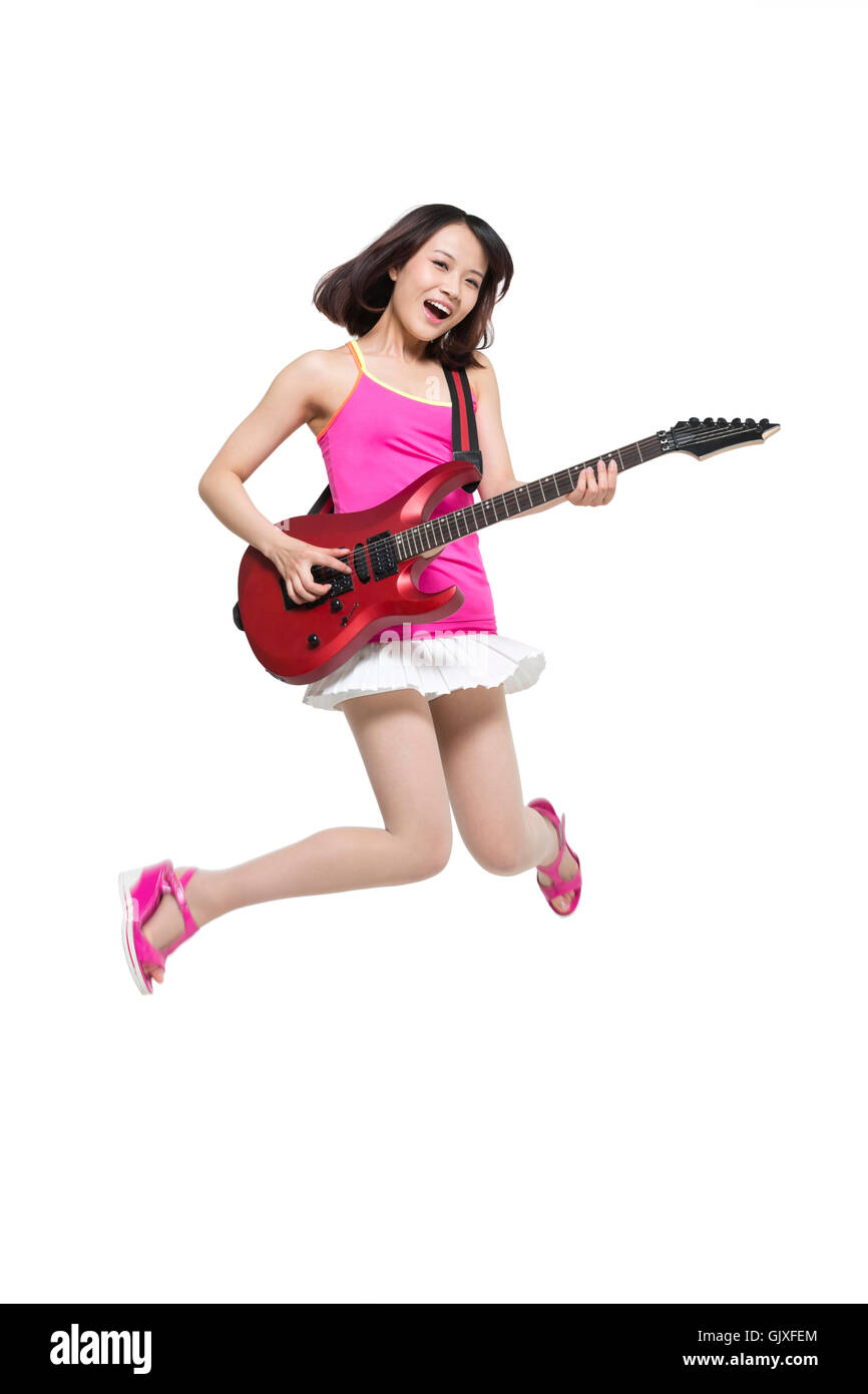 Fashion studio shot of young women while playing the guitar and dancing ...
