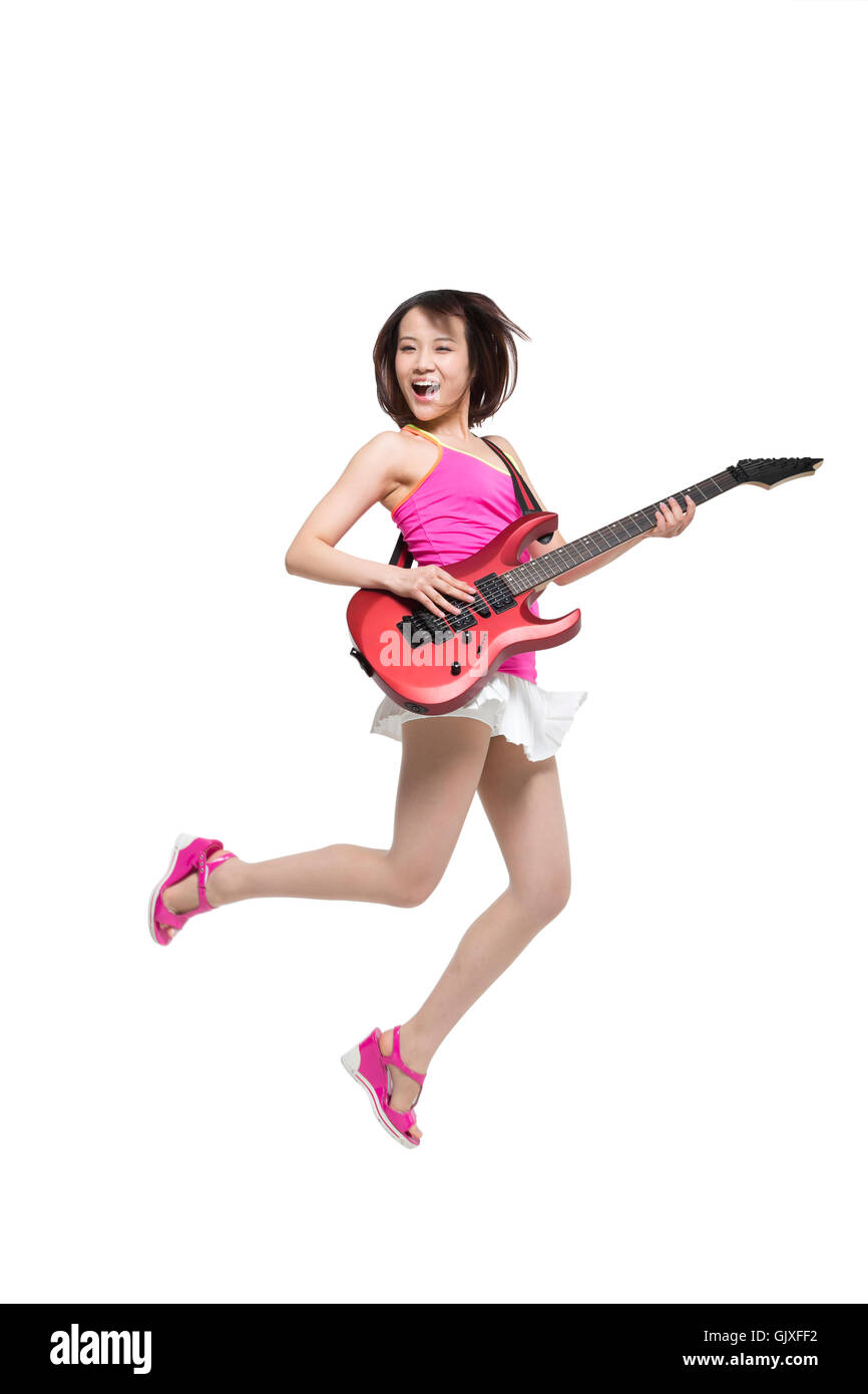 Fashion studio shot of young women while playing the guitar and dancing ...