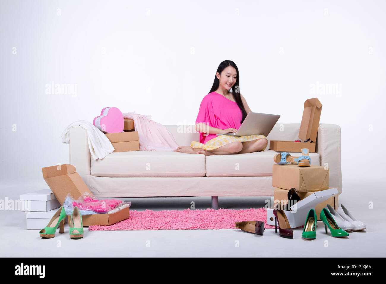 Studio shot Young woman sitting on the couch using laptop Stock Photo ...