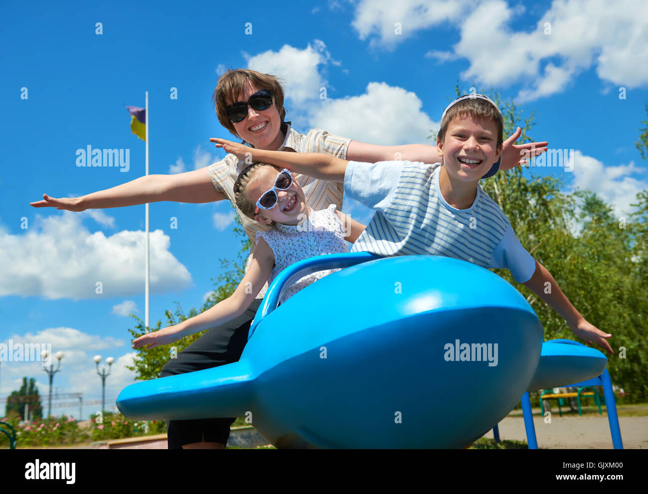 child and woman fly on blue airplane attraction in park, happy family ...