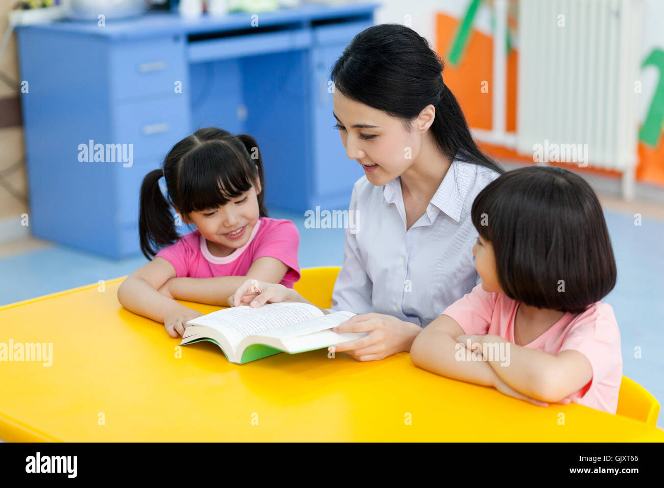 Female teachers and children learning together Stock Photo - Alamy