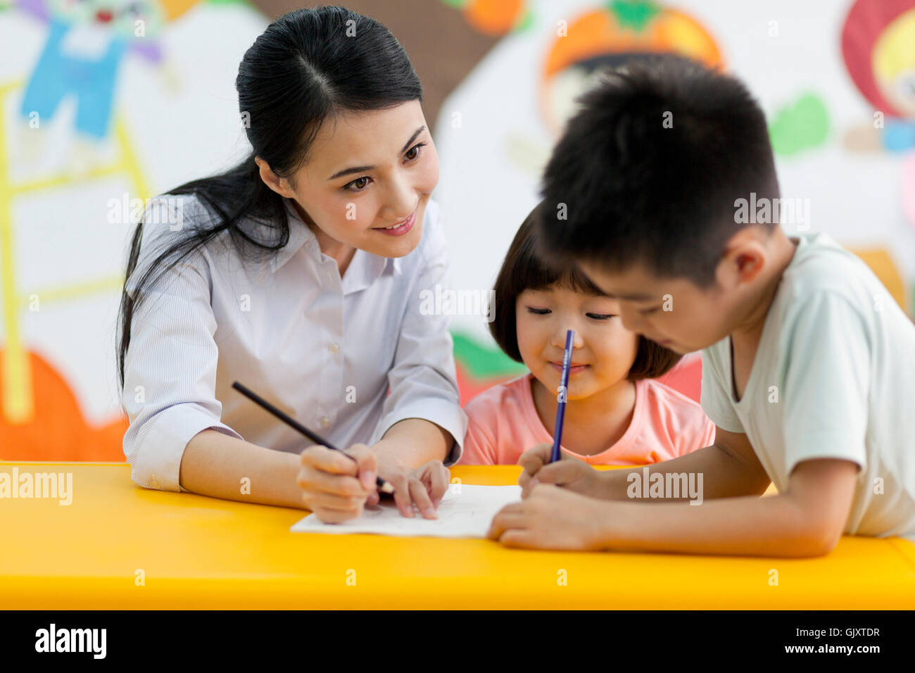 Female teachers and children learning together Stock Photo - Alamy