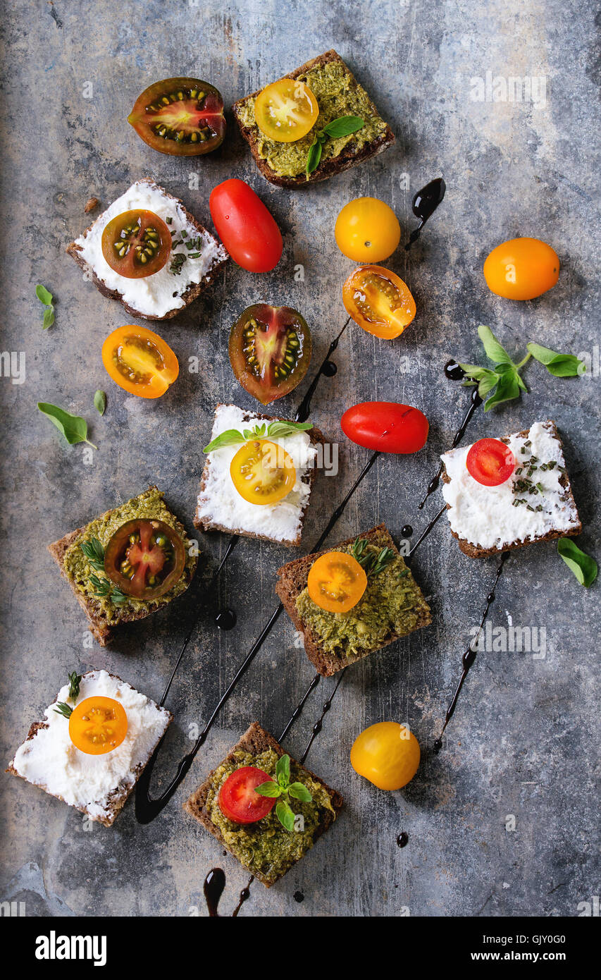 Variety of small rye sandwiches with colorful cherry tomatoes, ricotta ...