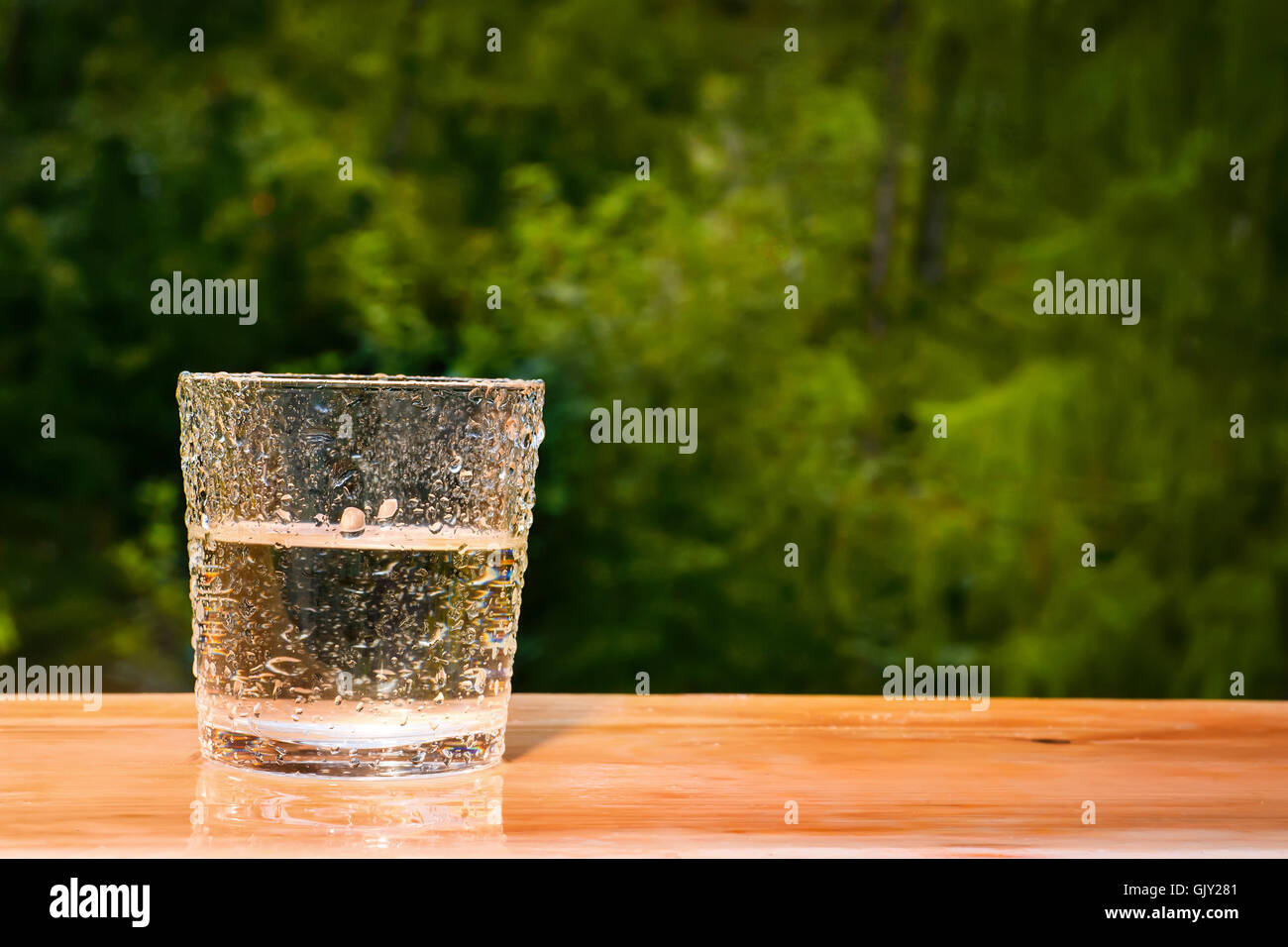 Wet drinking glass with water on green wood background Stock Photo - Alamy