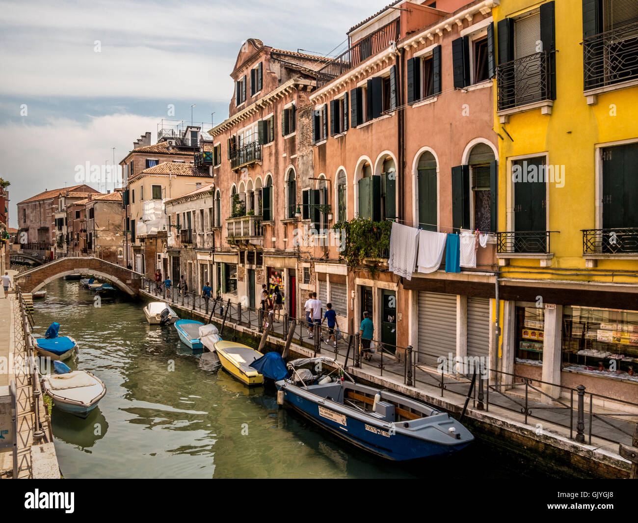 Moored boats on a narrow canal with traditional buildings either side ...
