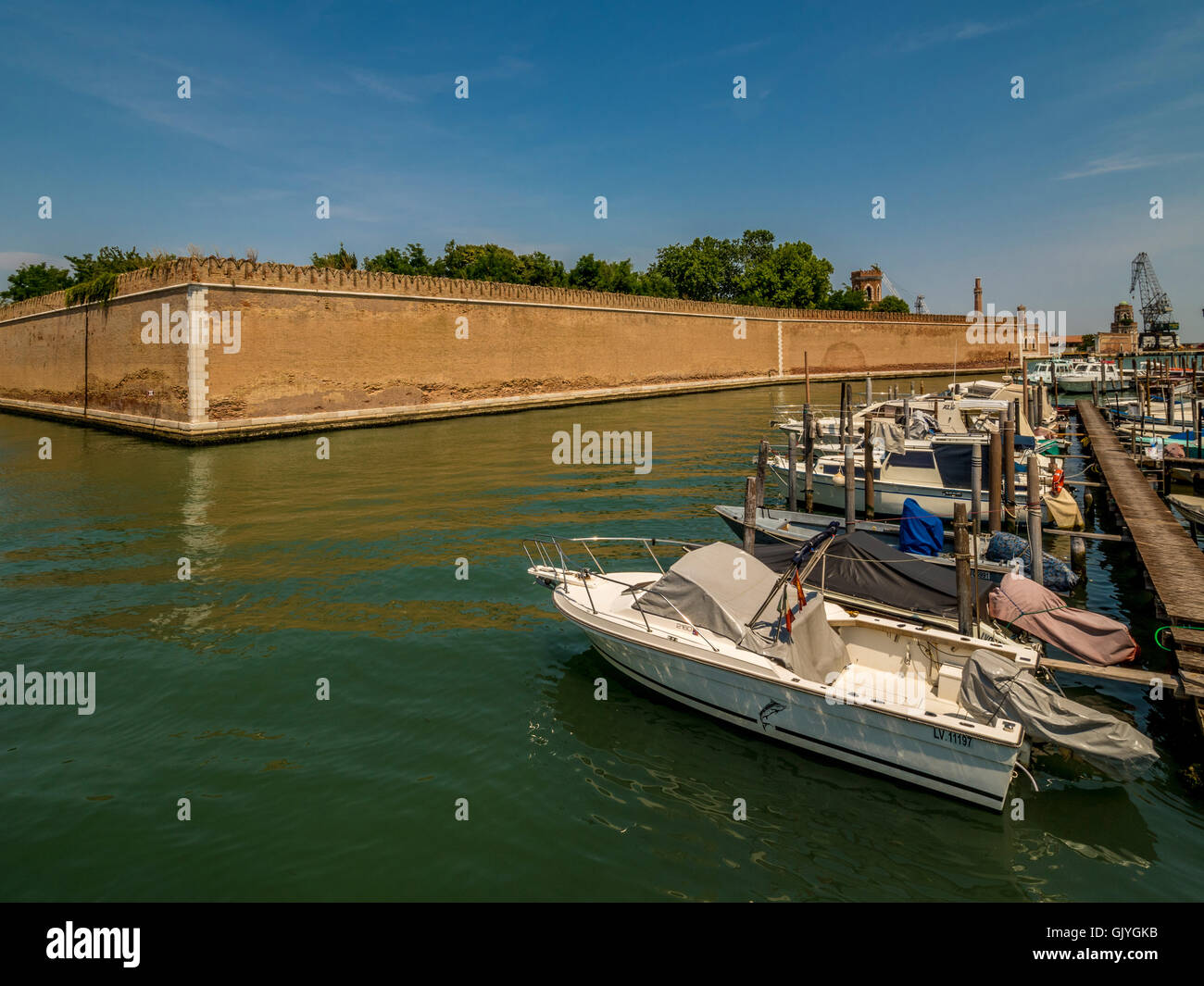 Perimeter wall of Arsanale with moored boats in the canal. Venice ...