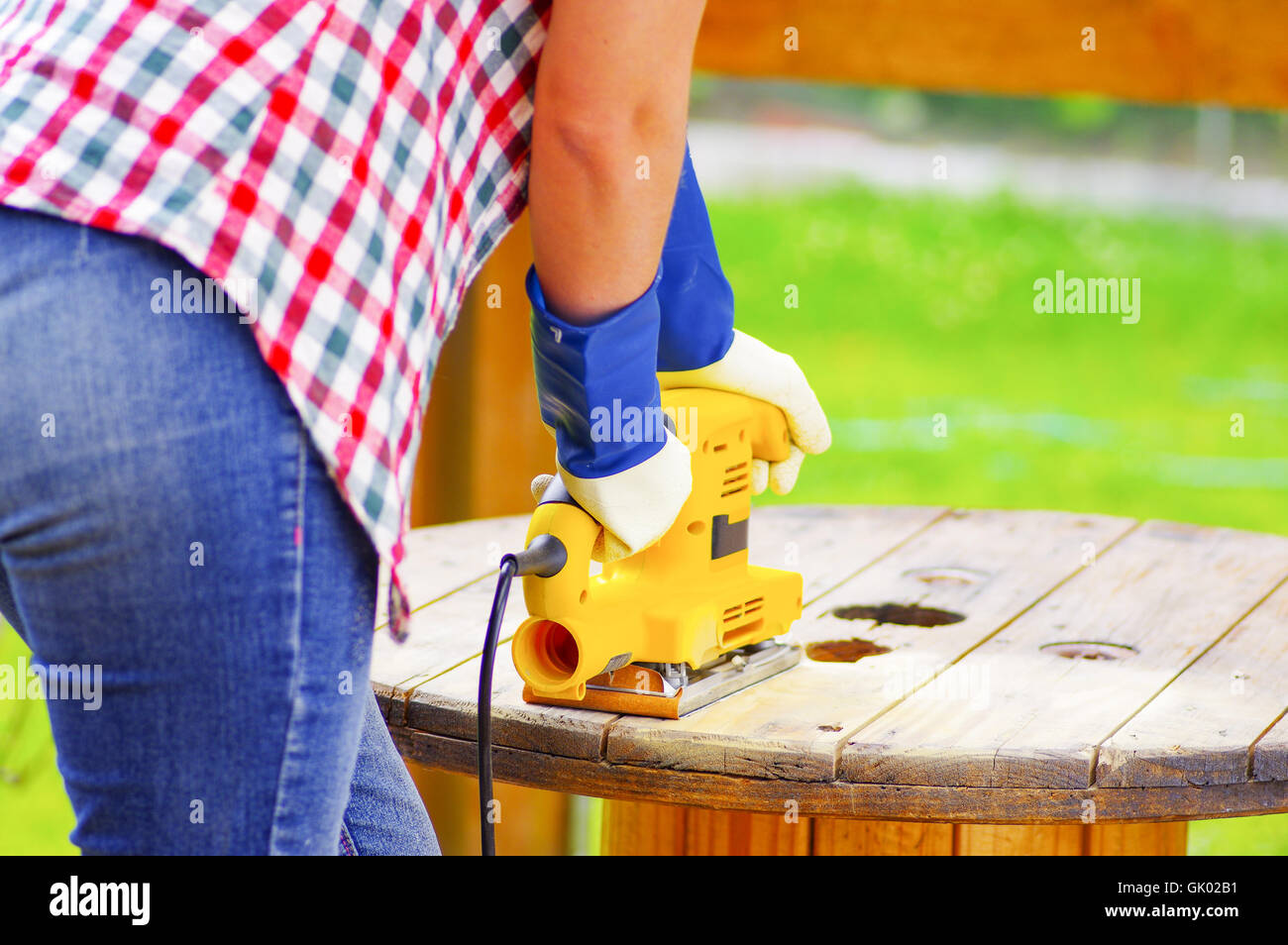 woman sanding a wood table with a yellow electric sander Stock Photo ...