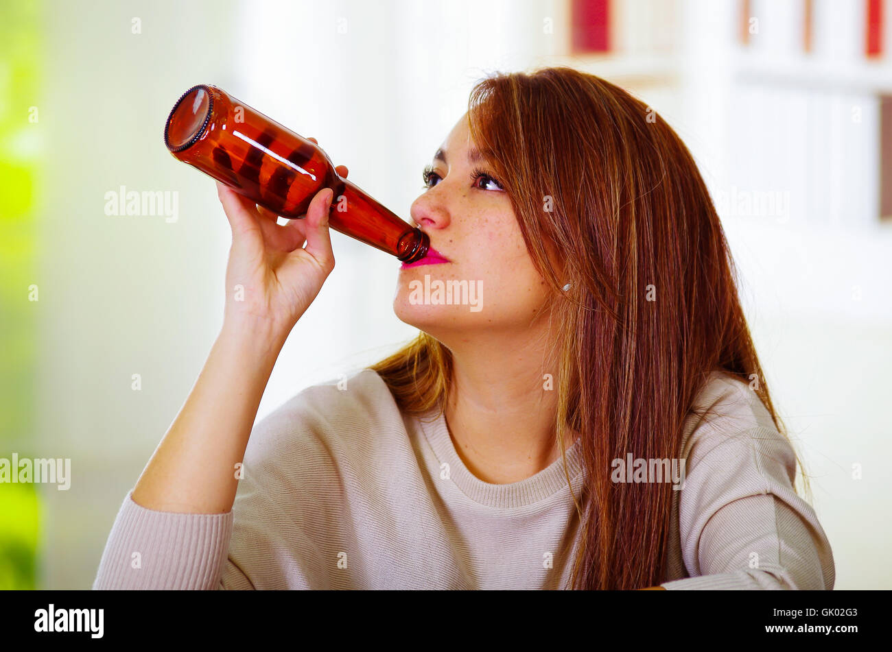 Attractive woman wearing white sweater sitting by bar counter drinking ...