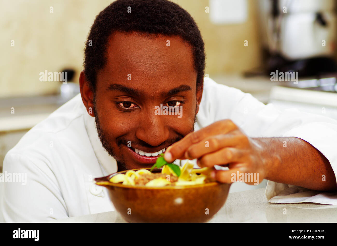 Happy chef wearing white clothes preparing bowl of food in professional ...