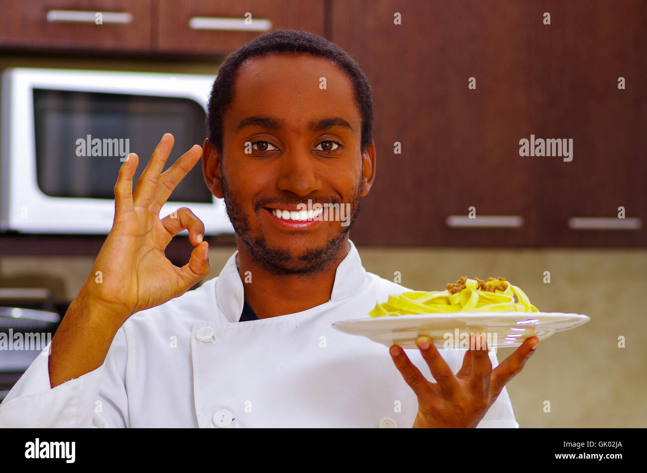 Satisfied chef wearing white clothes making circle with fingers ...