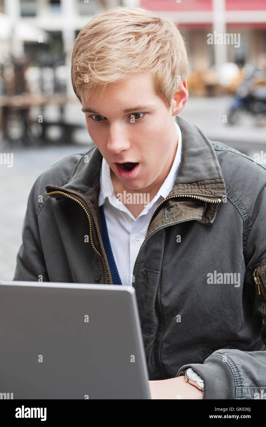 Shocked young man with laptop Stock Photo - Alamy