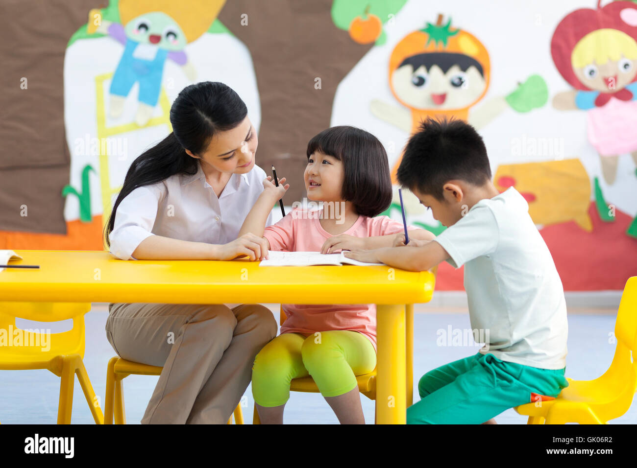 Female teachers and children learning together Stock Photo - Alamy