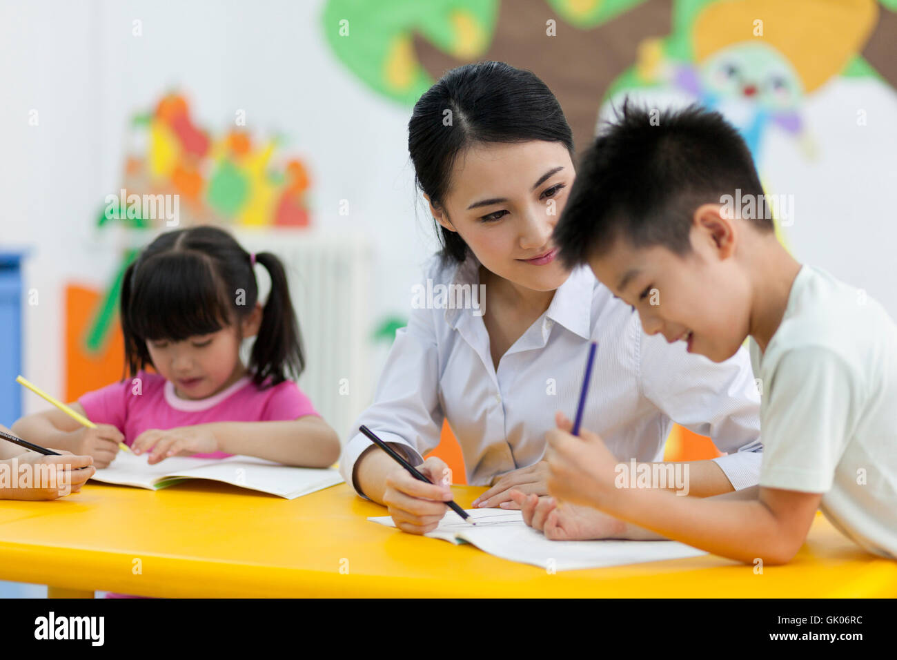 Female teachers and children learning together Stock Photo - Alamy