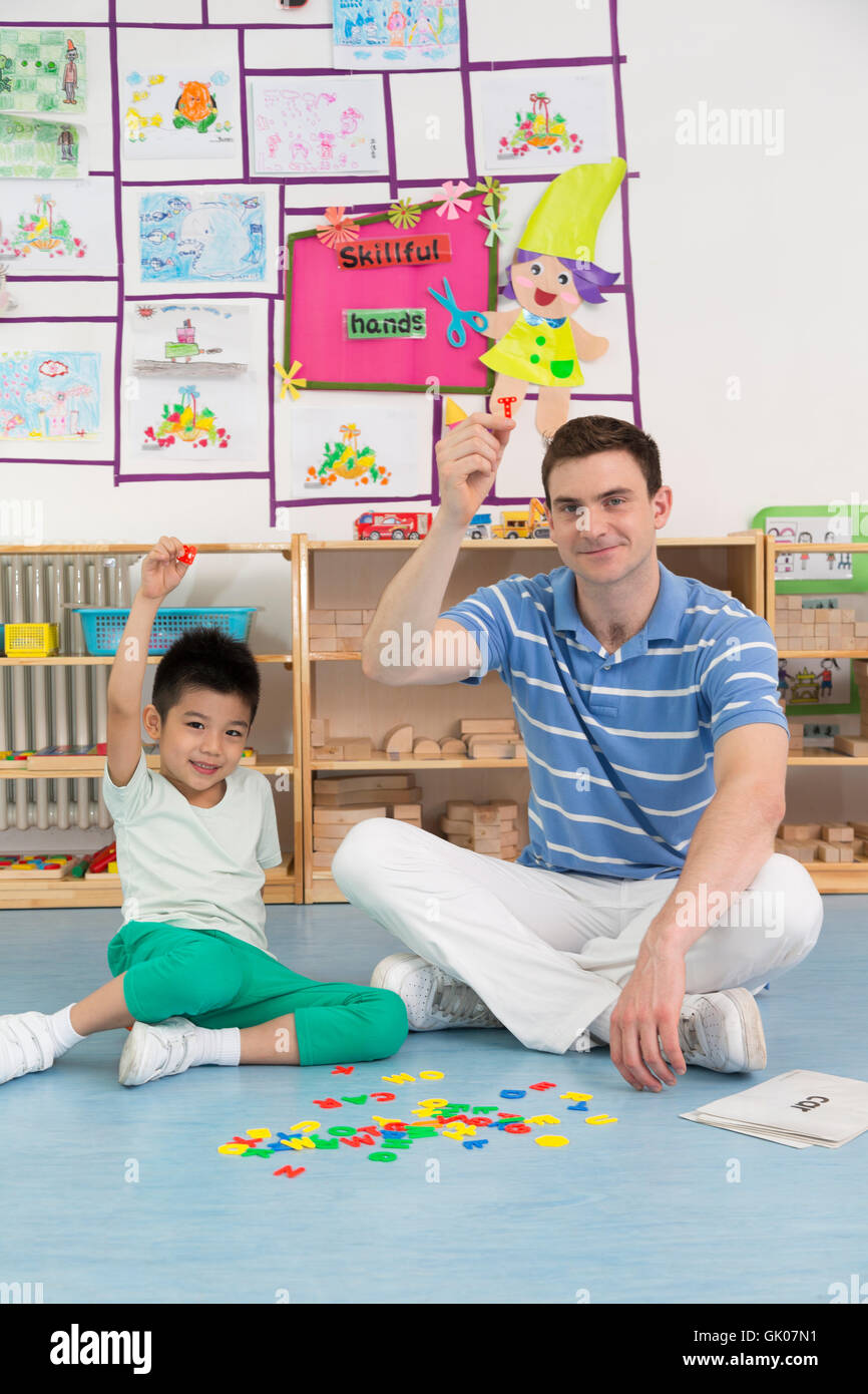 Male teacher and children playing together Stock Photo - Alamy