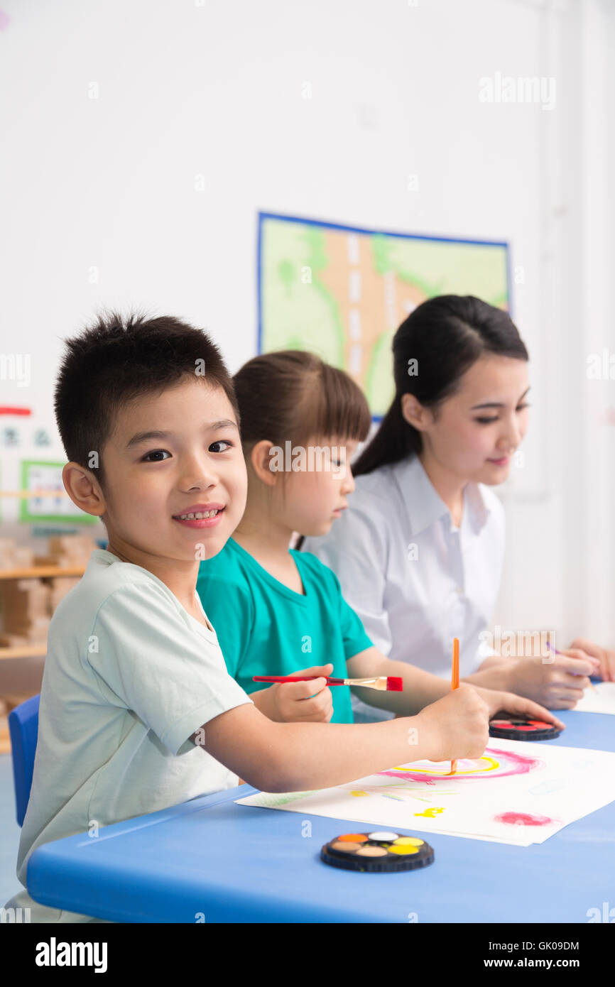 Female teachers and children play together Stock Photo - Alamy