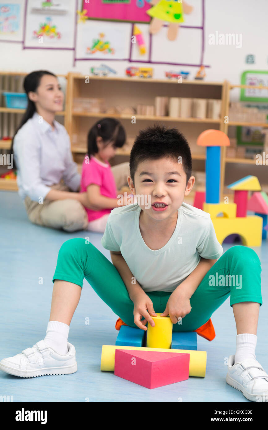 Female teachers and children play together Stock Photo - Alamy