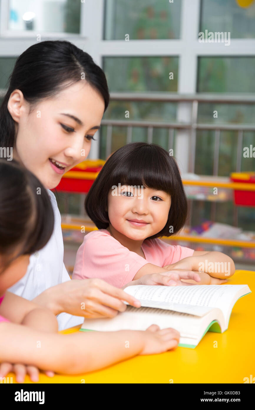 Female teachers and children play together Stock Photo - Alamy