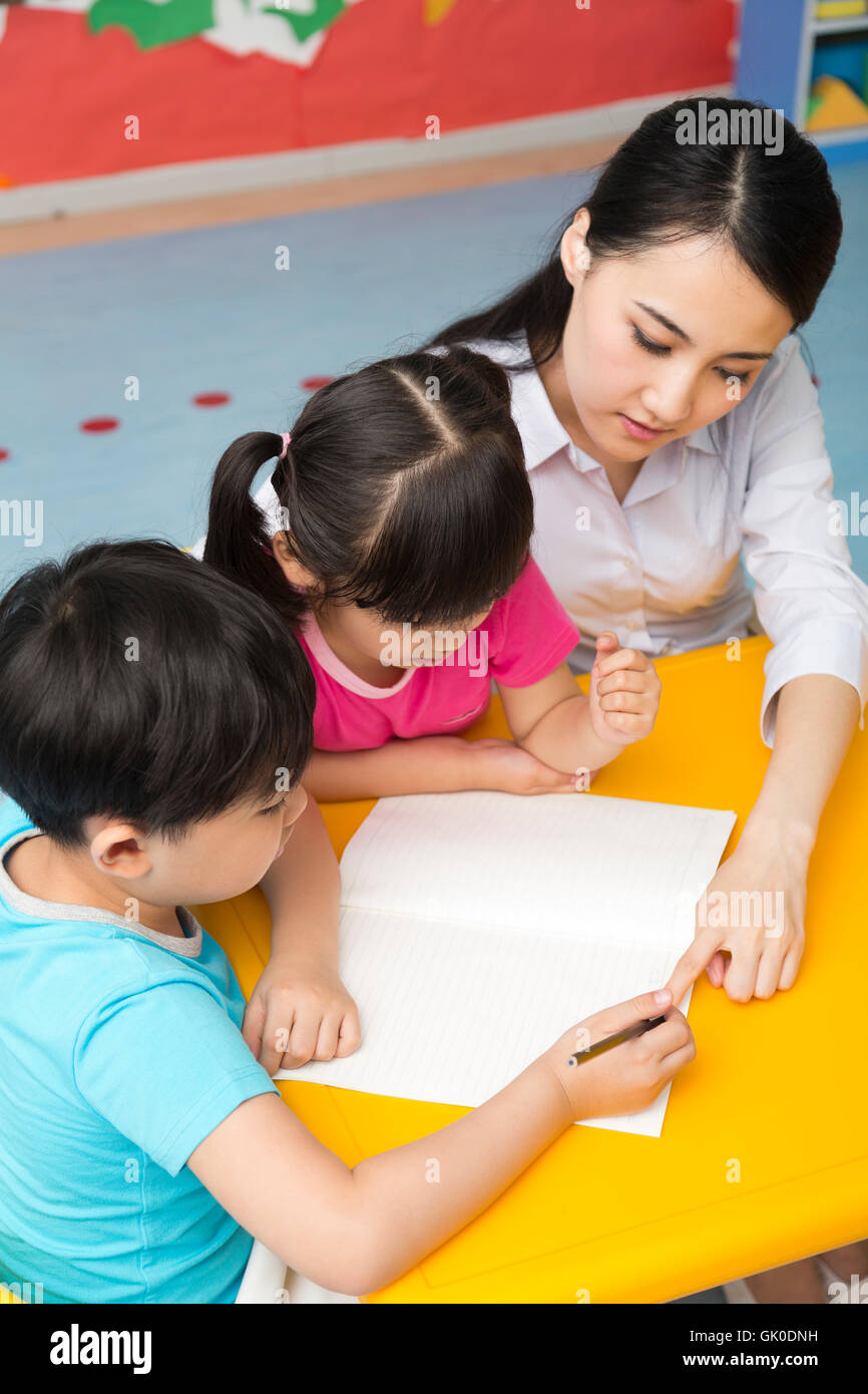 Female teachers and children play together Stock Photo - Alamy