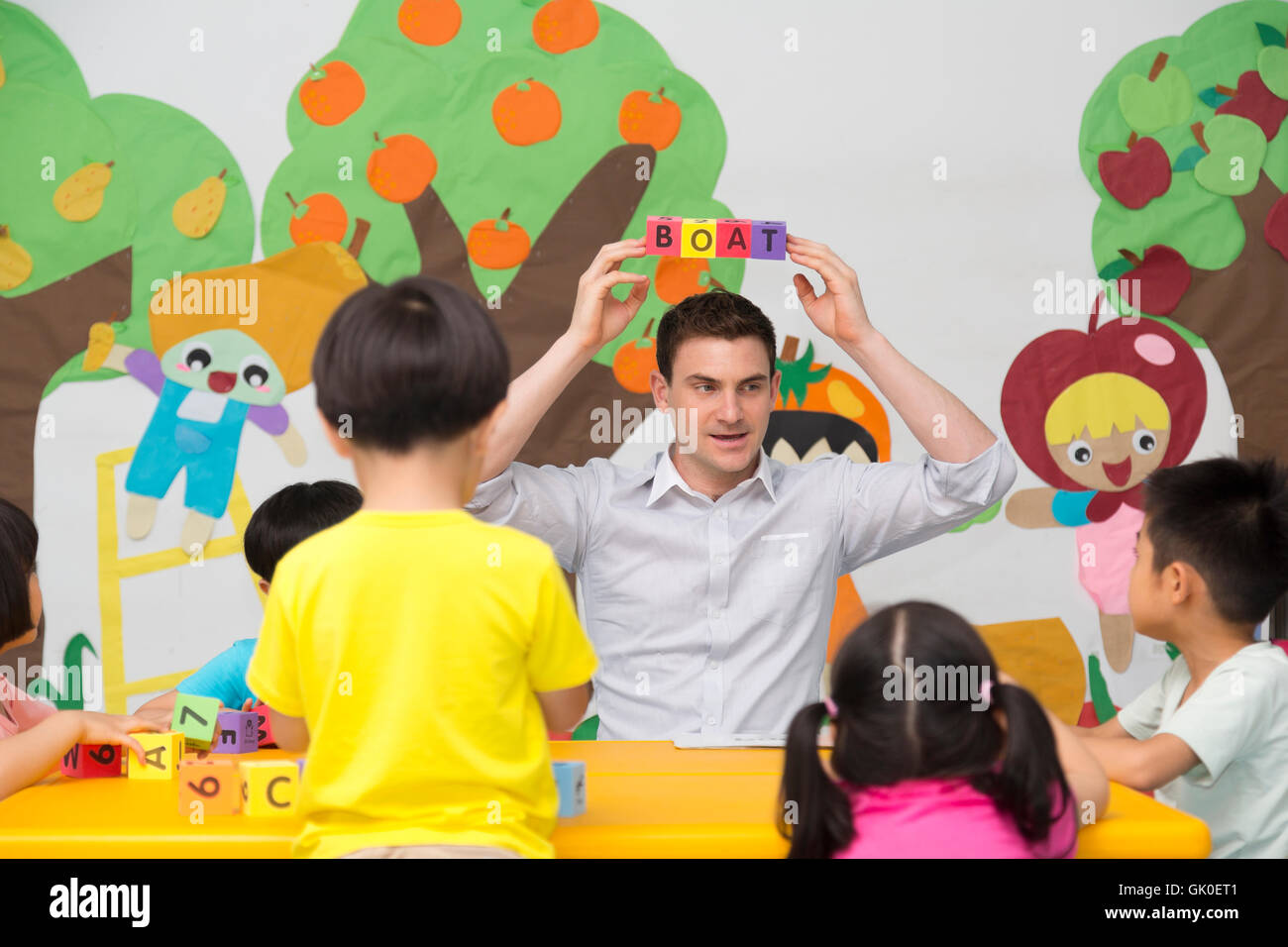 Male teacher and children playing together Stock Photo - Alamy
