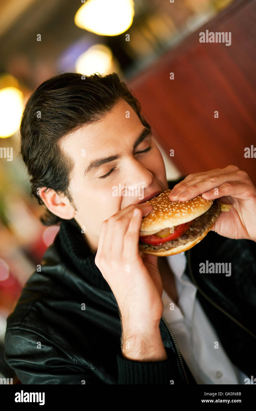 man in restaurant eating hamburger Stock Photo - Alamy
