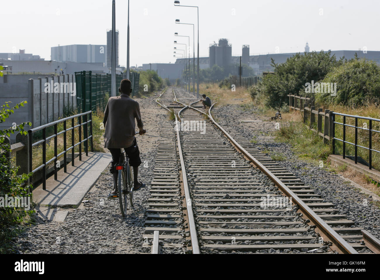 Calais, France. 17th Aug, 2016. A refugee cycles along the track of a ...