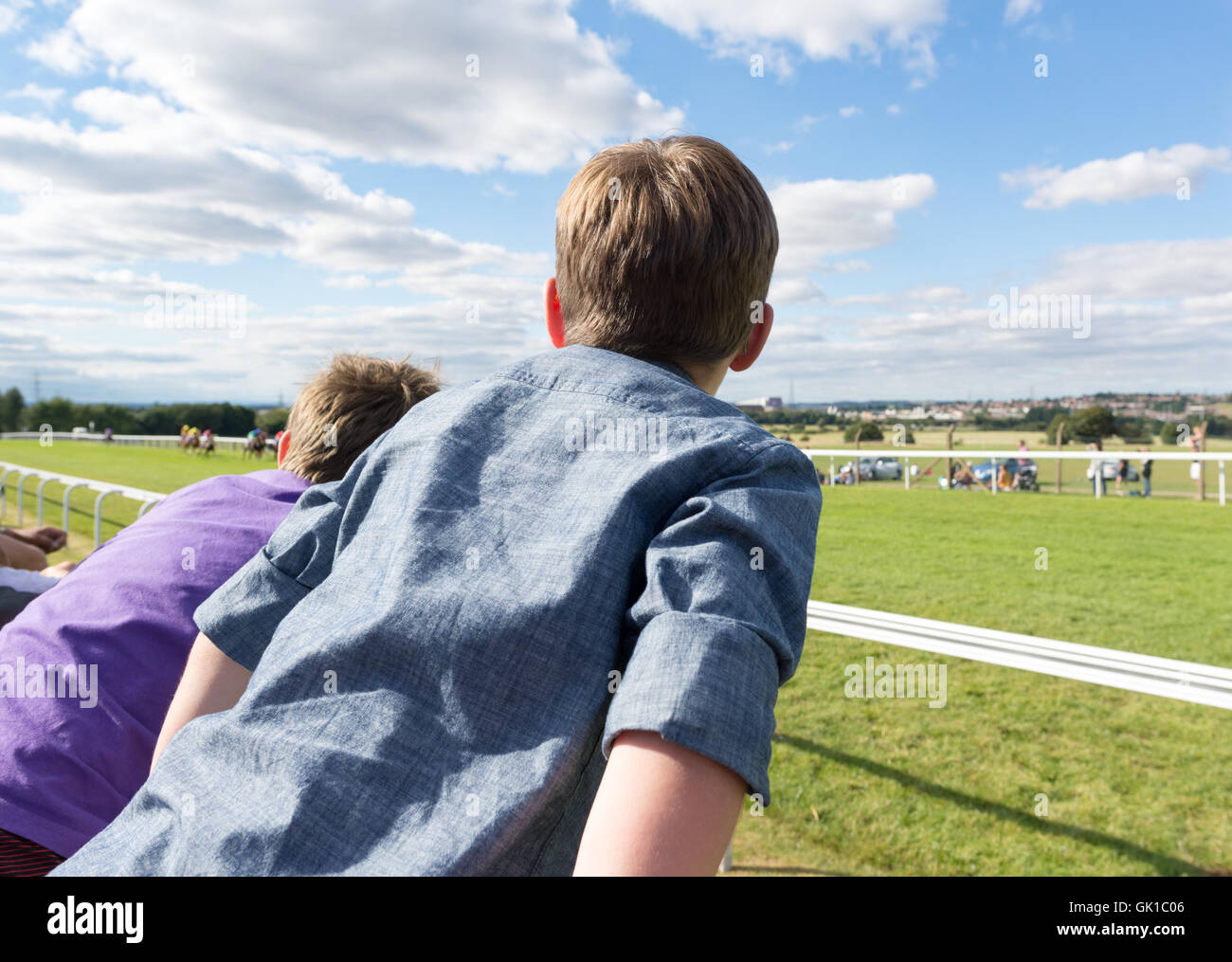 Getting the best view. Two boys hoist themselves up the fence to get a ...